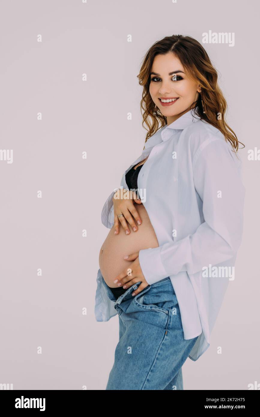 Side view of woman looking at pregnant belly posing against white ...
