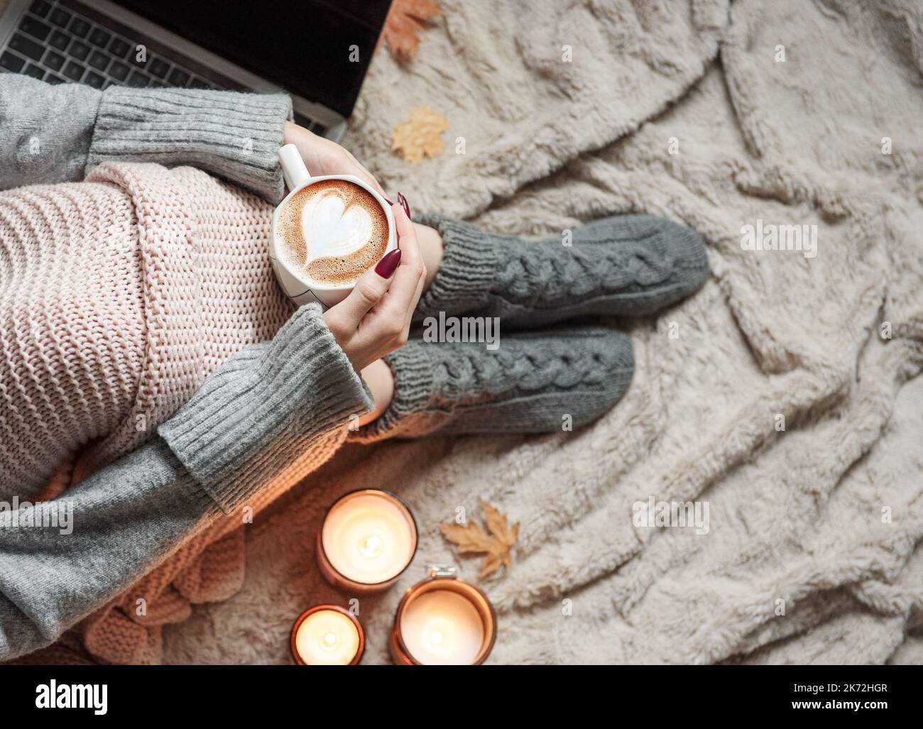 Cozy home, woman covered with warm blanket, drinks coffee and works on ...