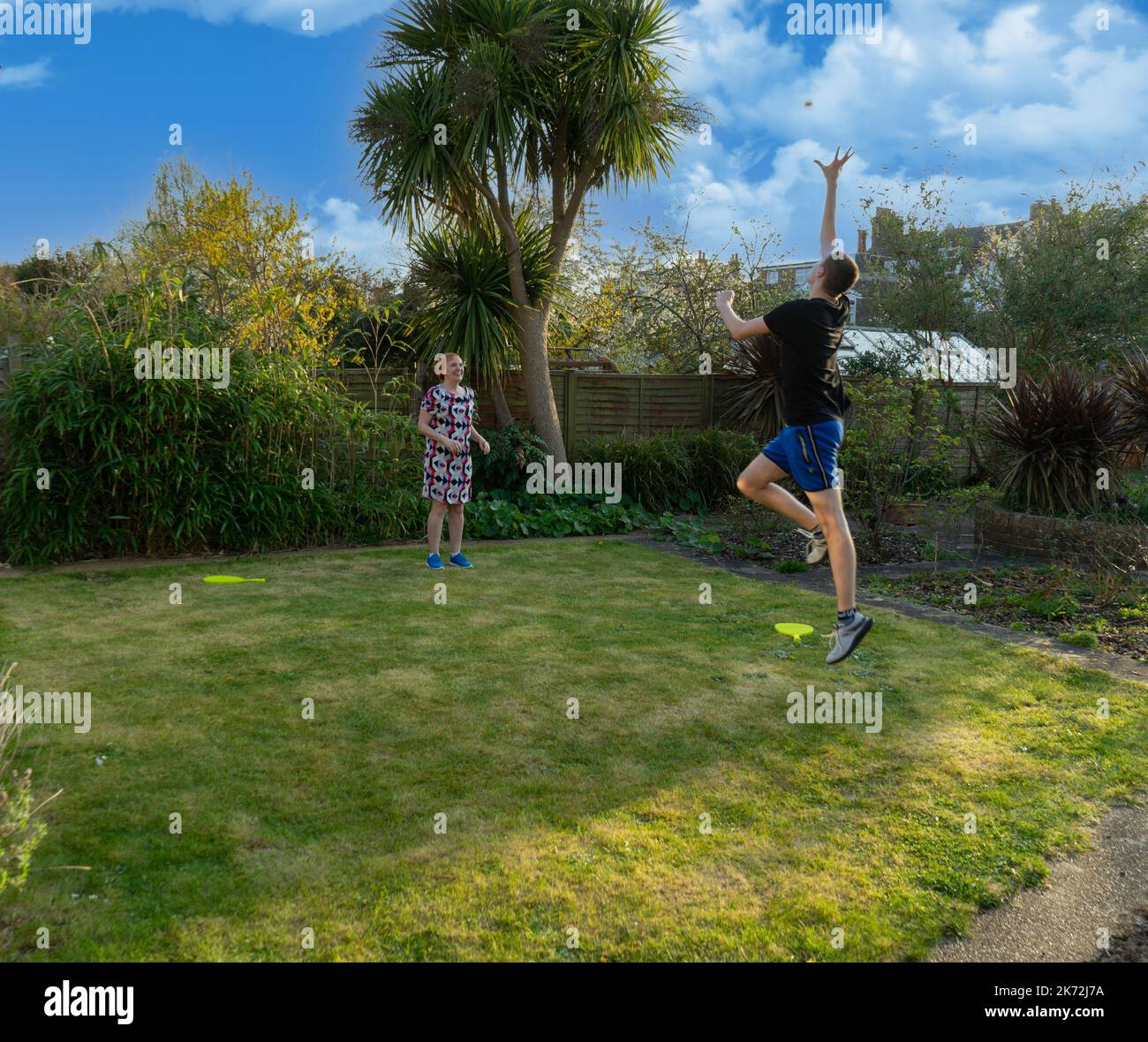 Teenage boy wearing sports gear jumping high to catch a tennis ball ...