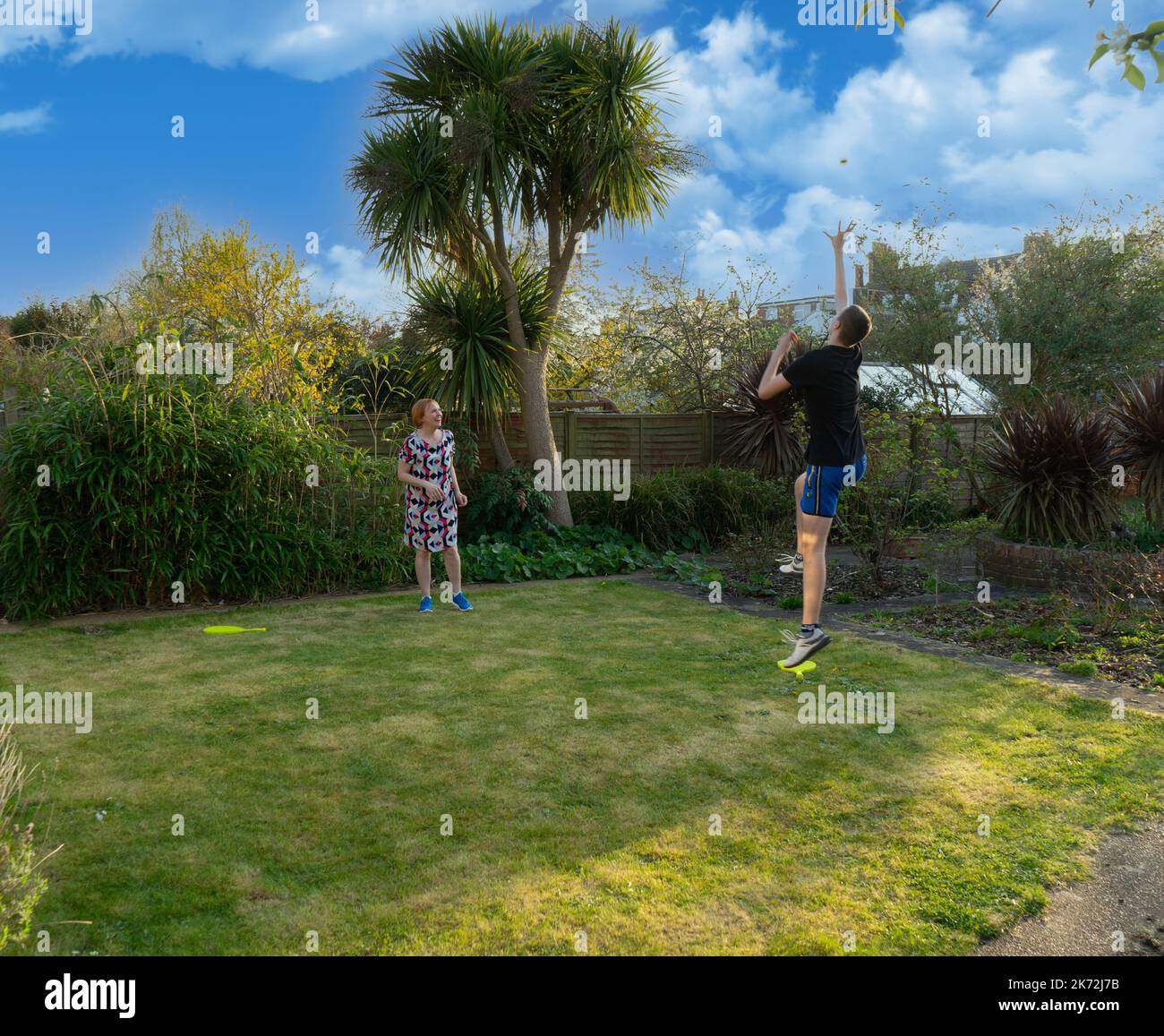 Teenage boy wearing sports gear jumping high to catch a tennis ball ...