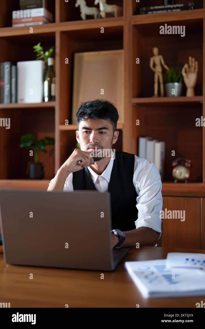 A portrait of a good-looking and discreet Asian man sitting at his desk ...