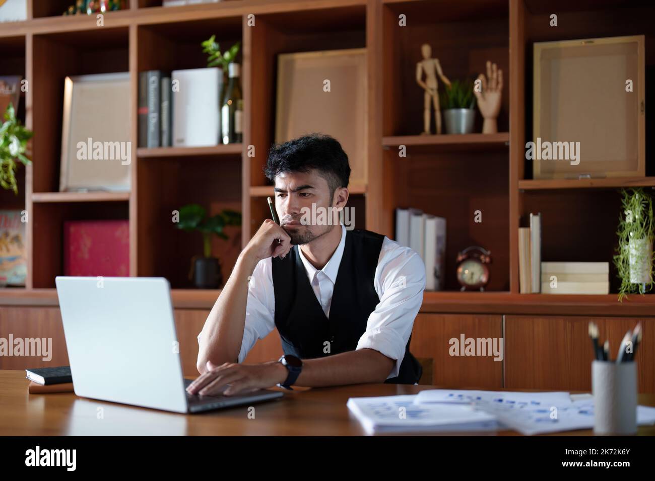A portrait of a good-looking and discreet Asian man sitting at his desk ...