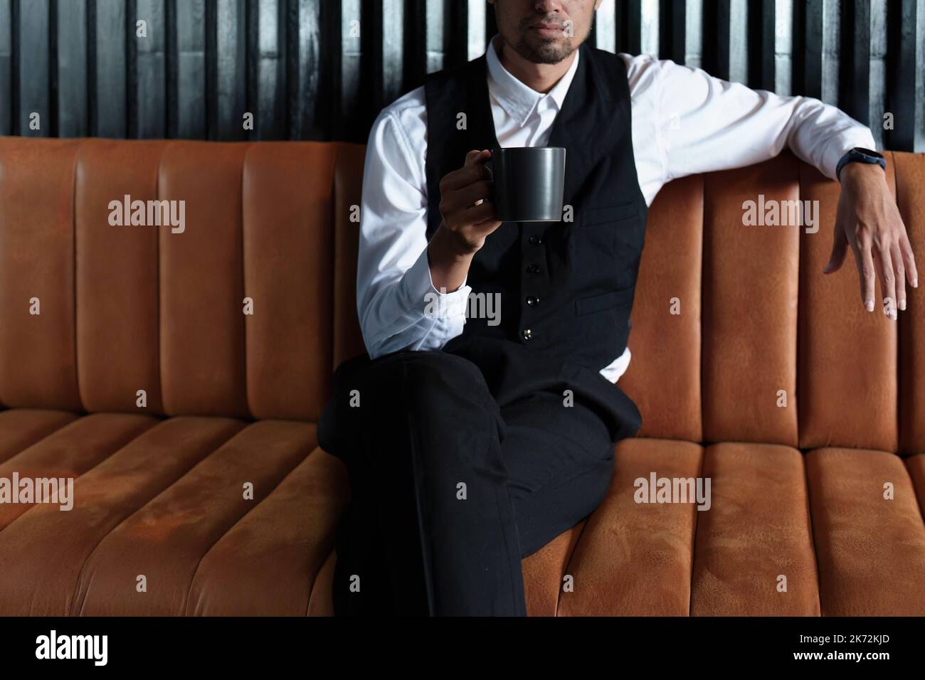Portrait of a good looking and discreet Asian man sitting on the sofa ...