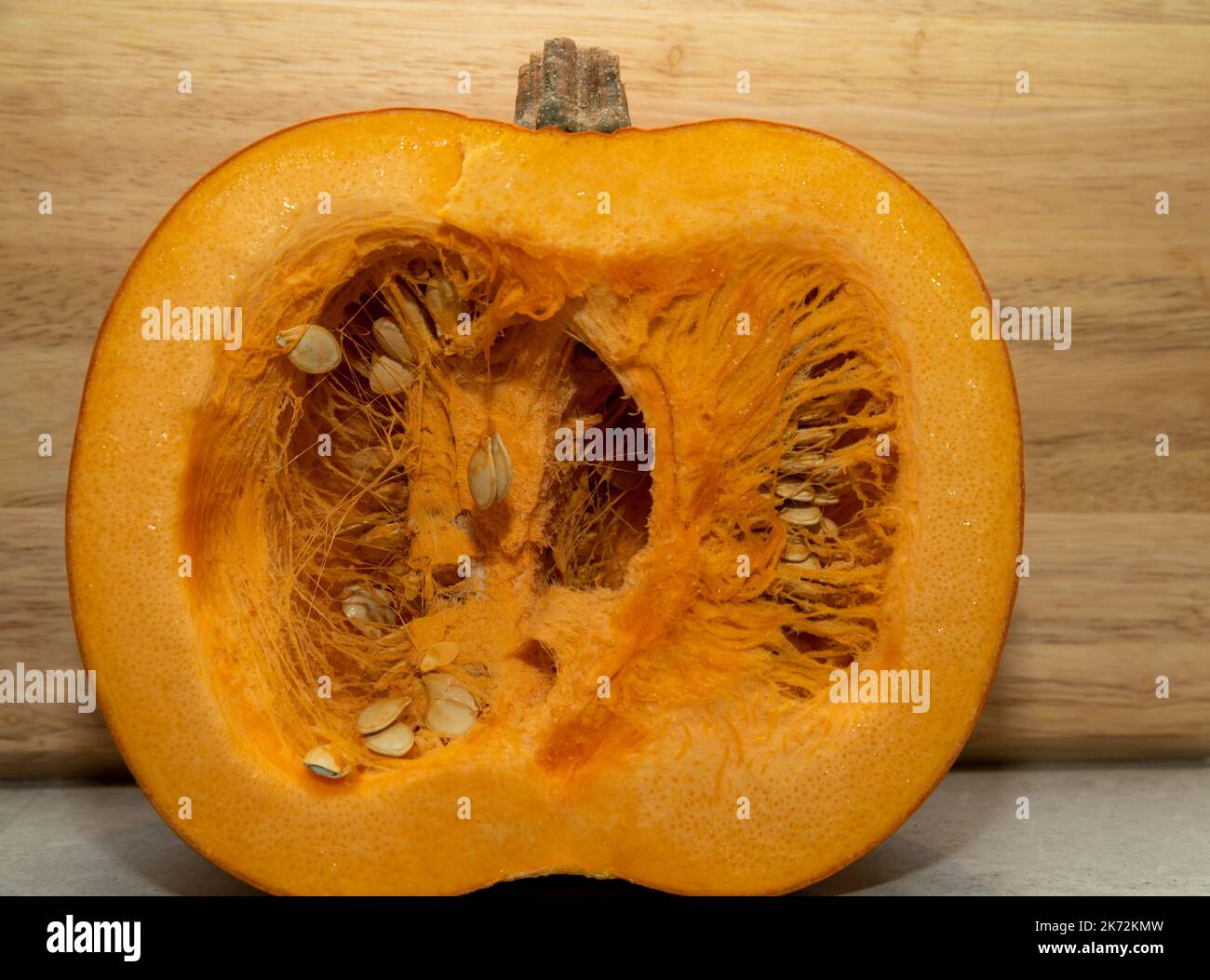 A large Pumpkin cut in half showing the seeds and pulp in the middle ...