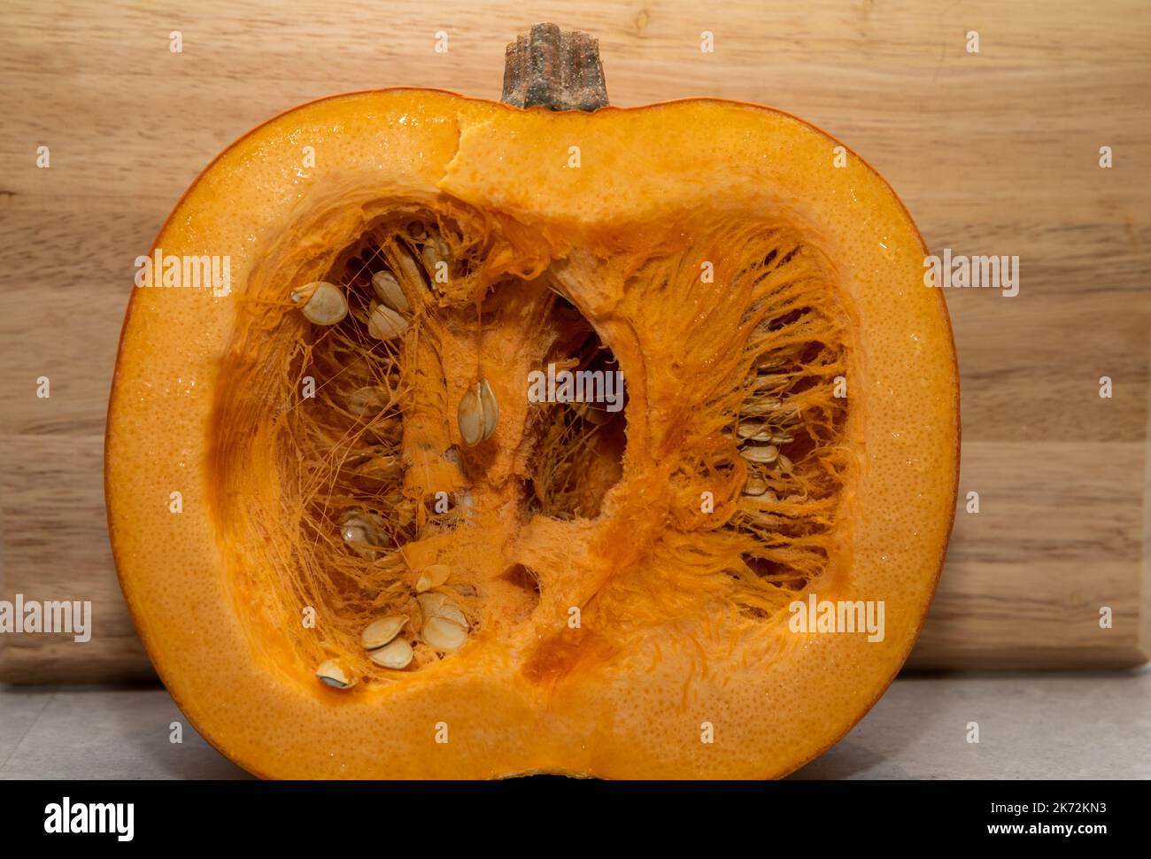 A large Pumpkin cut in half showing the seeds and pulp in the middle ...