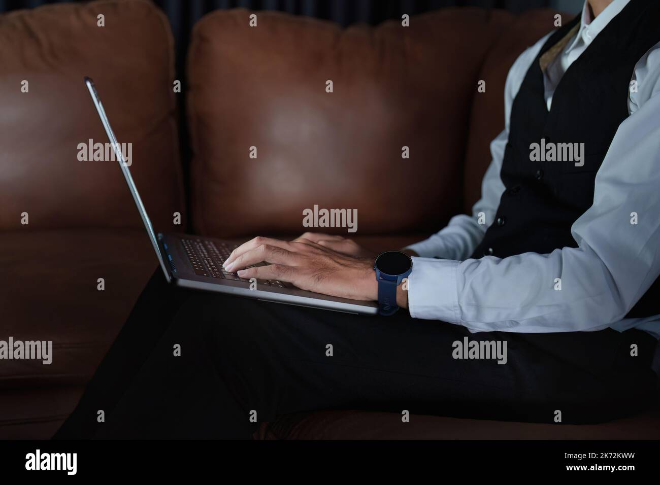 Portrait of a handsome, discreet Asian man sitting on the sofa using a ...