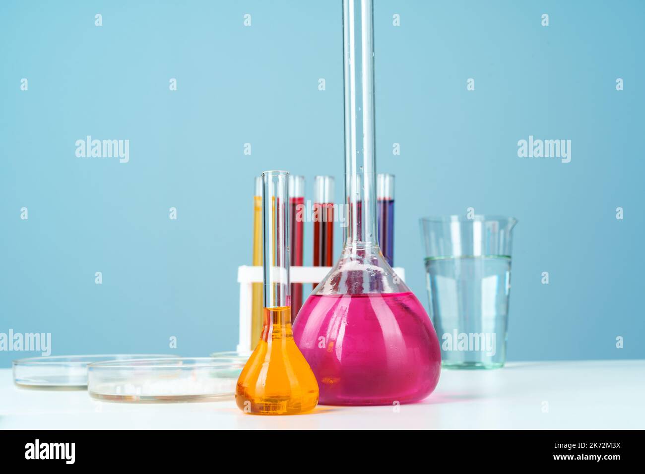 Chemical laboratory glassware with various colored liquids on table ...