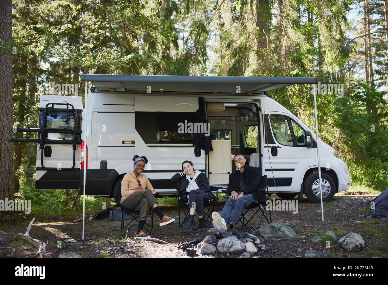 Friends relaxing in front of camper van Stock Photo - Alamy