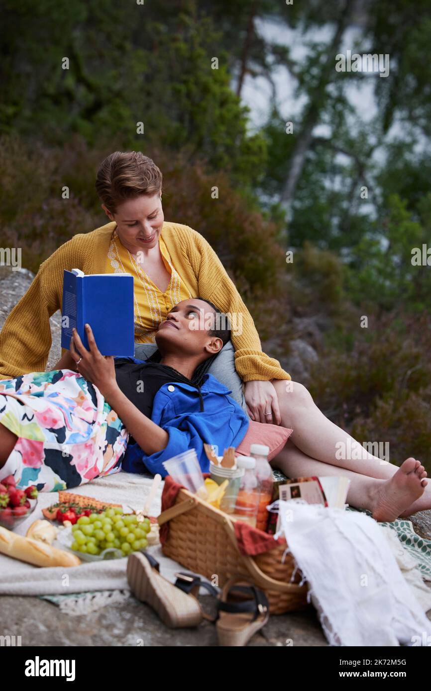 Female couple having picnic and reading book Stock Photo - Alamy