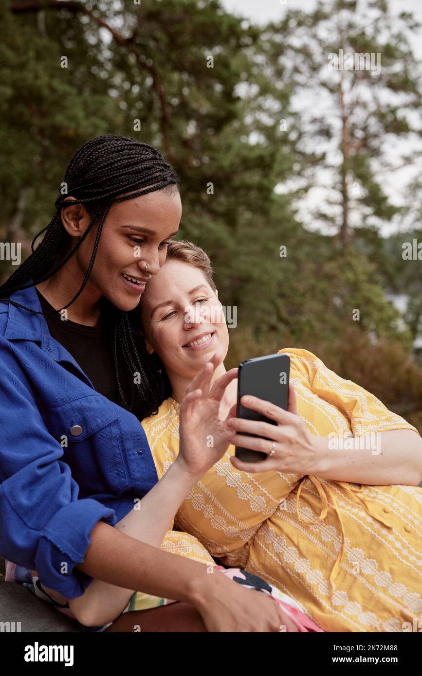 Female couple using phone outdoors Stock Photo - Alamy