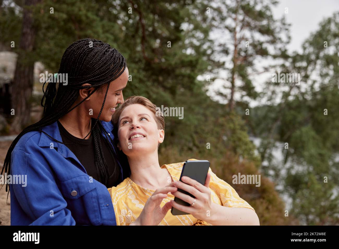 Female couple using phone outdoors Stock Photo - Alamy