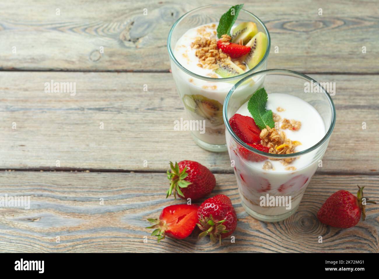 glass of healthy strawberry yogurt with fresh berries on wooden table ...