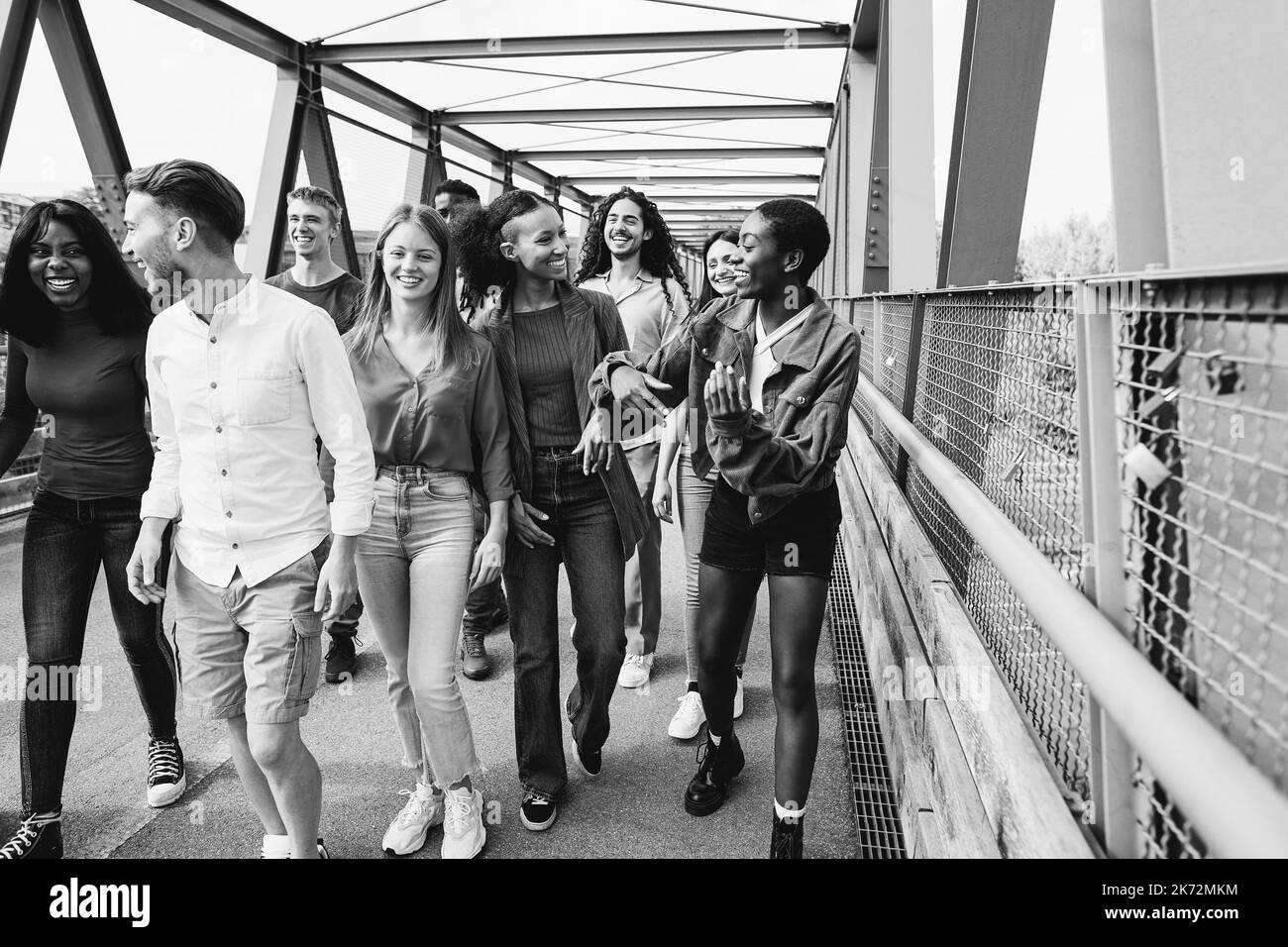 Multiracial friends having fun outdoor walking across the bridge ...
