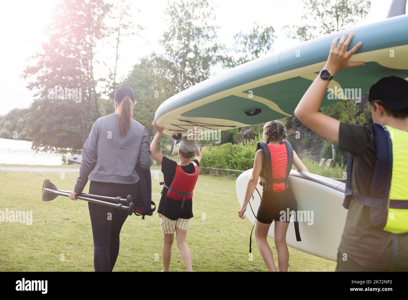 Mother and children carrying paddle board Stock Photo - Alamy