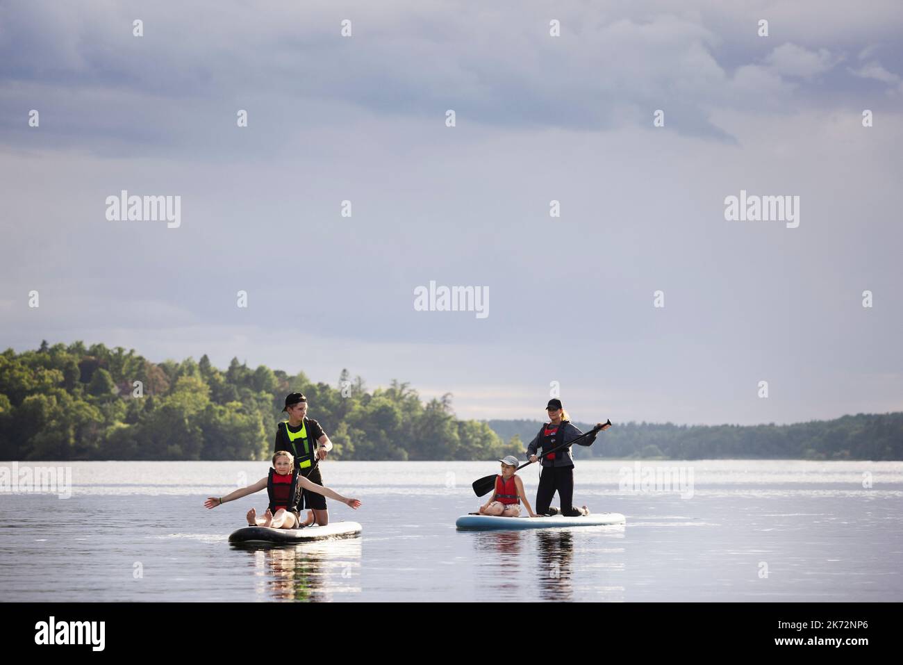 Mother and children paddle boarding Stock Photo - Alamy