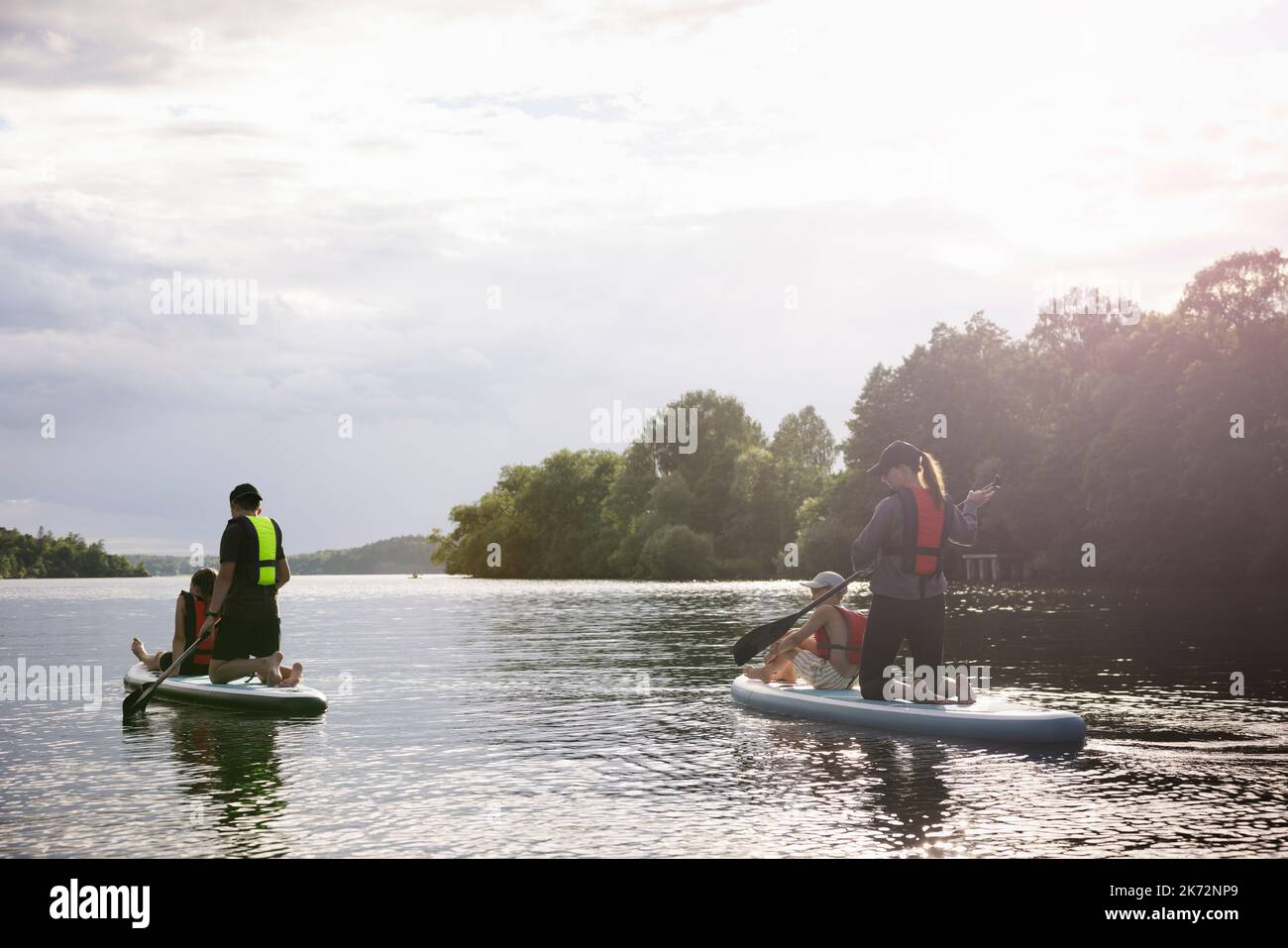 Mother and children paddle boarding Stock Photo - Alamy