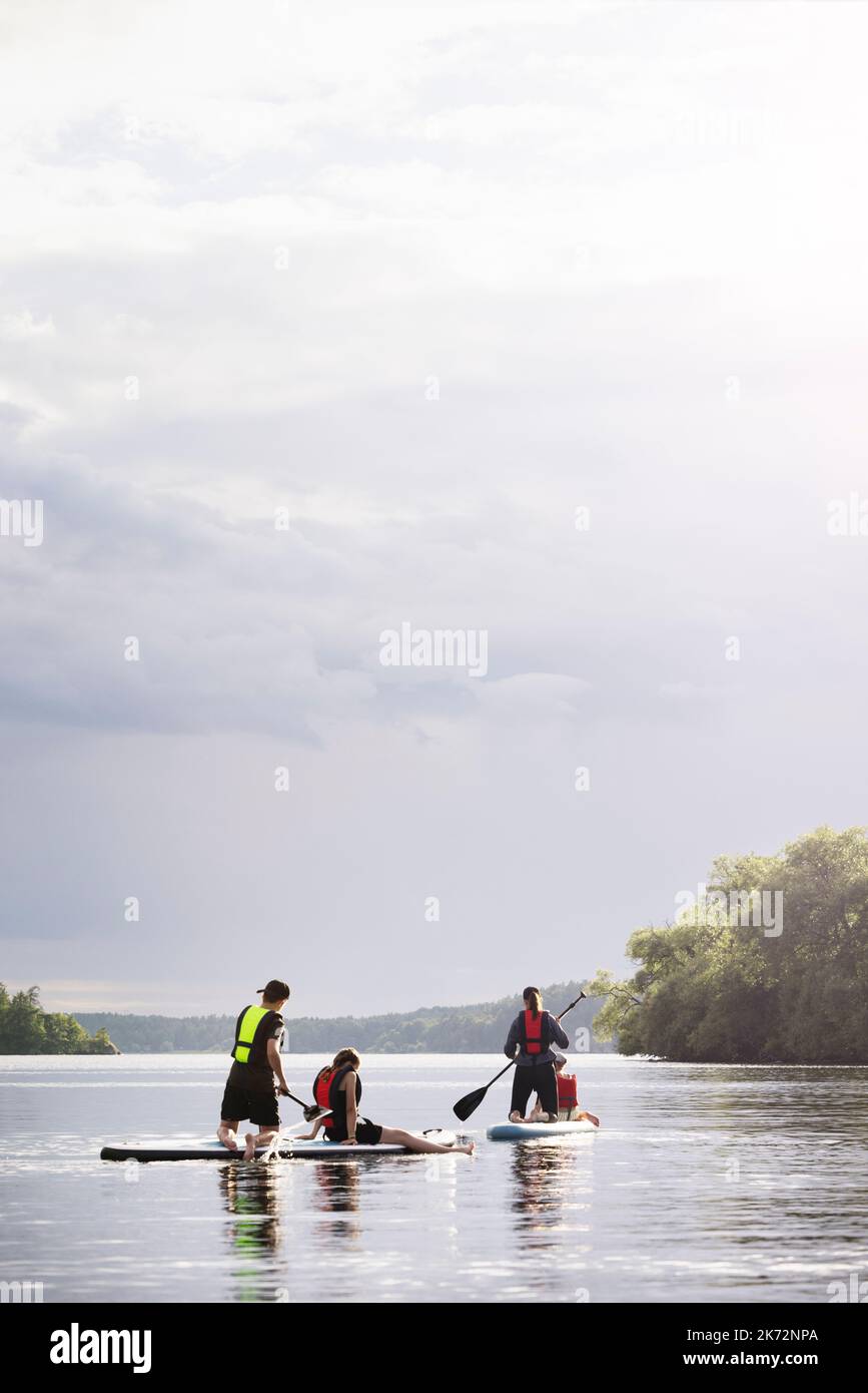 Mother and children paddle boarding Stock Photo - Alamy