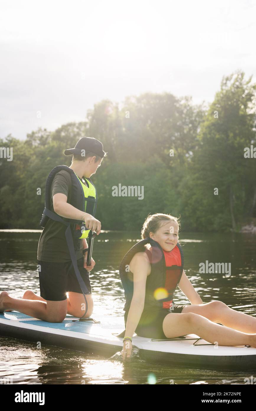 Brother and sister paddle boarding Stock Photo - Alamy