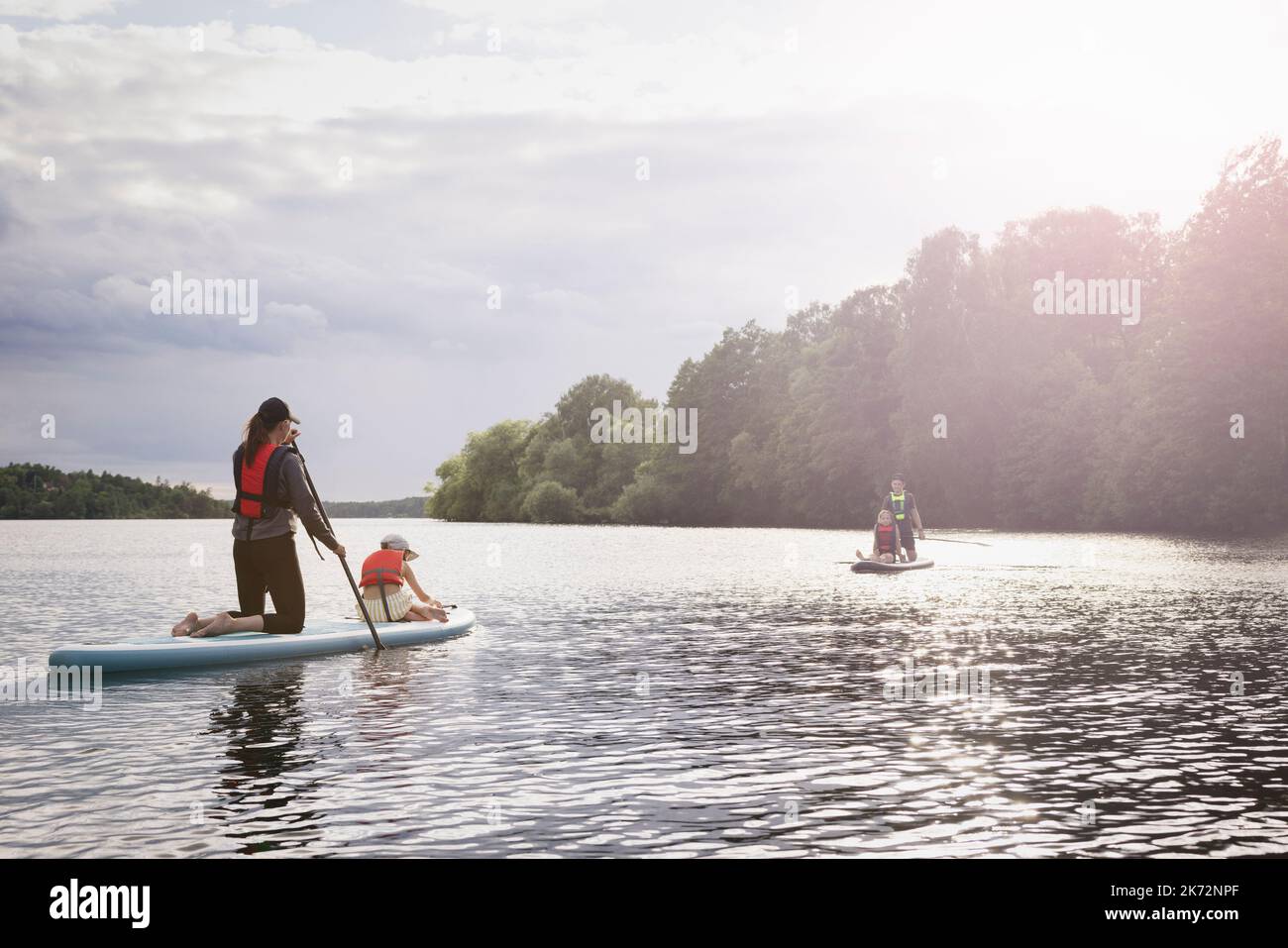 Mother and children paddle boarding Stock Photo - Alamy