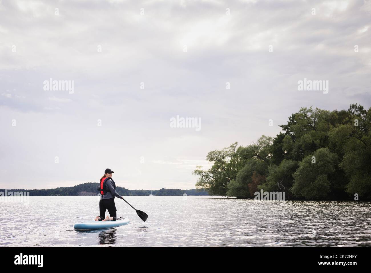 Woman paddle boarding on river Stock Photo - Alamy