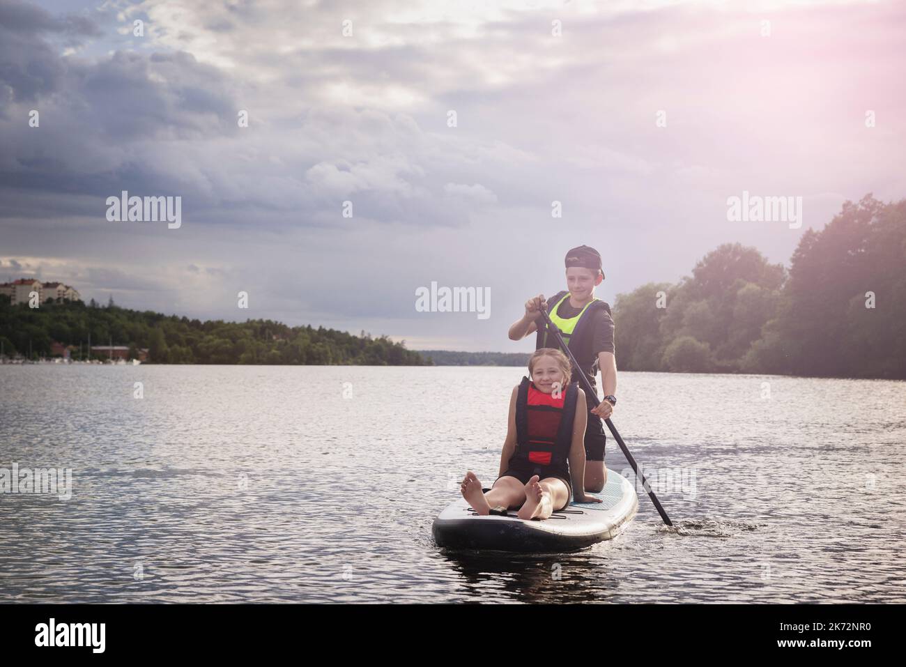 Brother and sister paddle boarding Stock Photo - Alamy