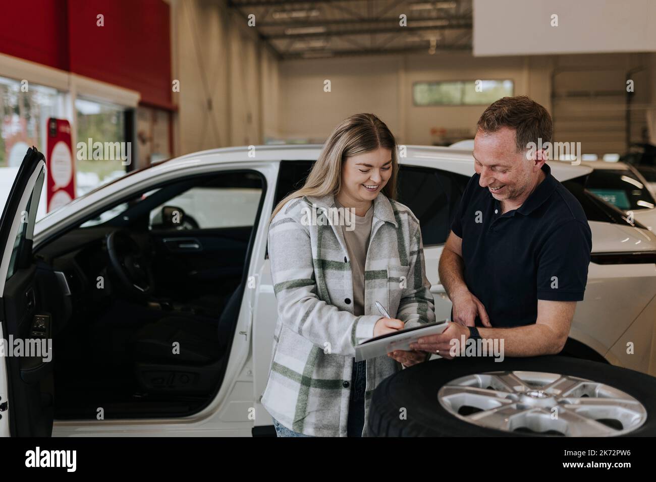 Woman signing contract in car dealership Stock Photo - Alamy
