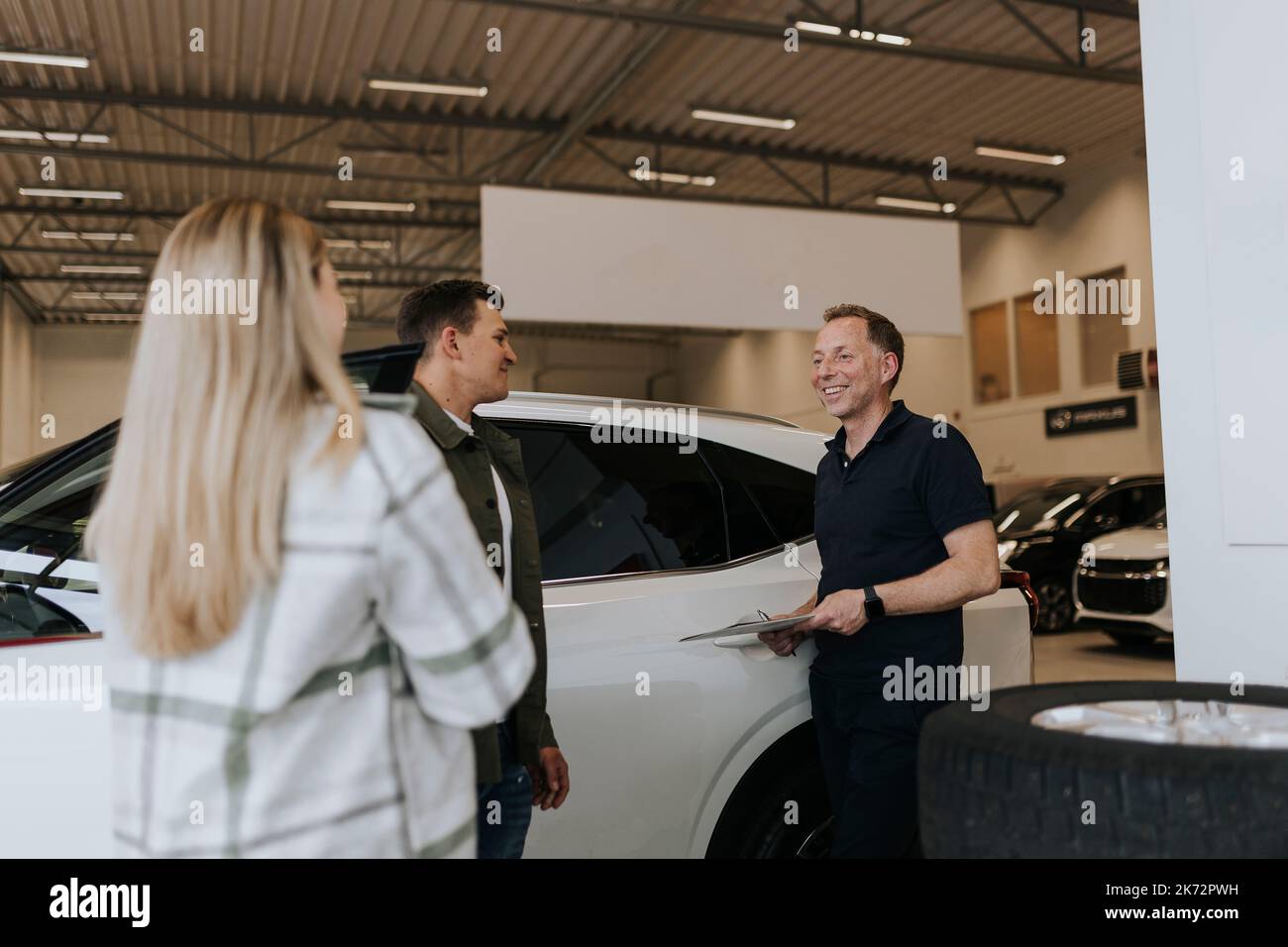 Salesman talking to customers in car dealership Stock Photo - Alamy