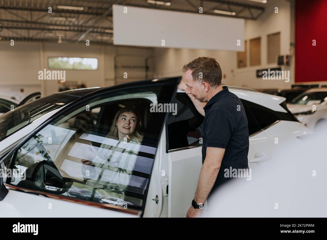 Salesman and female customer in car dealership Stock Photo - Alamy