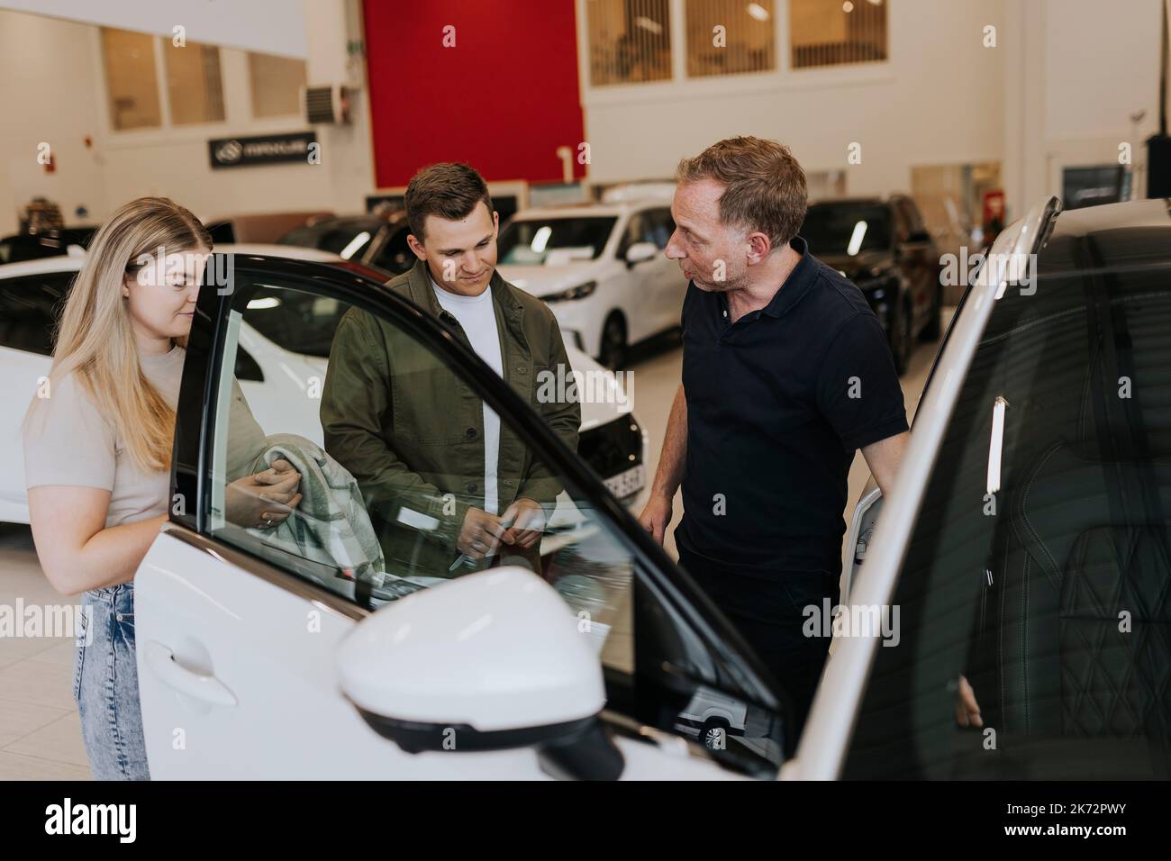Salesman talking to customers in car dealership Stock Photo - Alamy