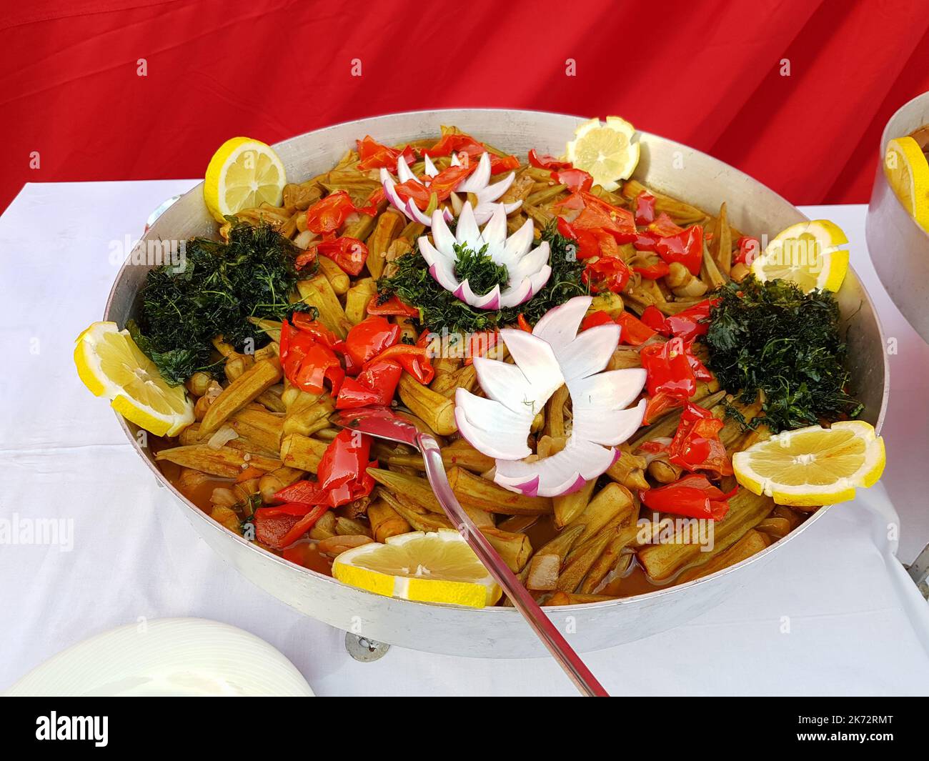 Stewed okra with red pepper, garnished with lemon, onion and herbs ...