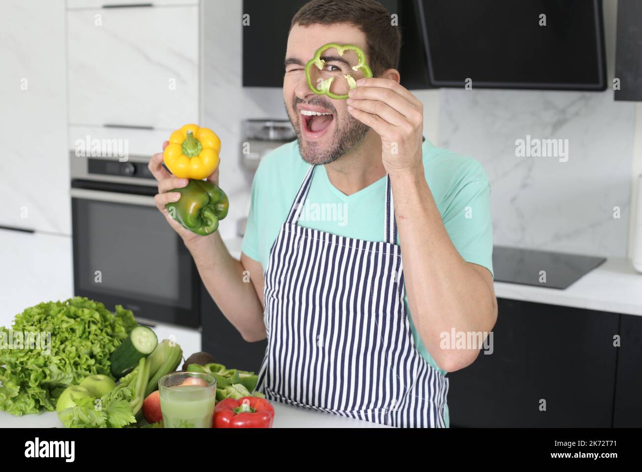 Man playing with green bell peppers in the kitchen Stock Photo - Alamy