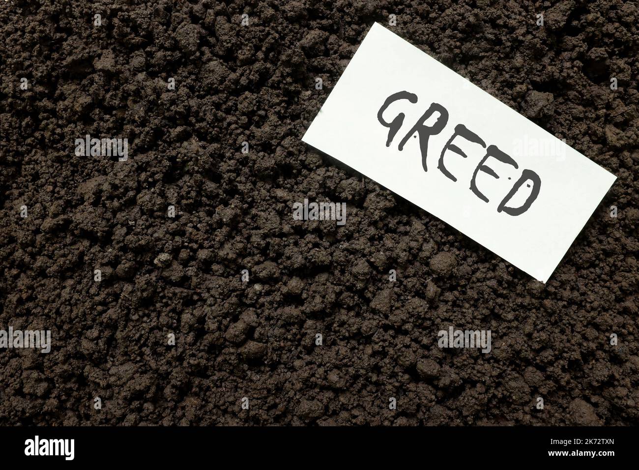 Greed or greedy concept. Paper note with handwritten word on dark soil ...