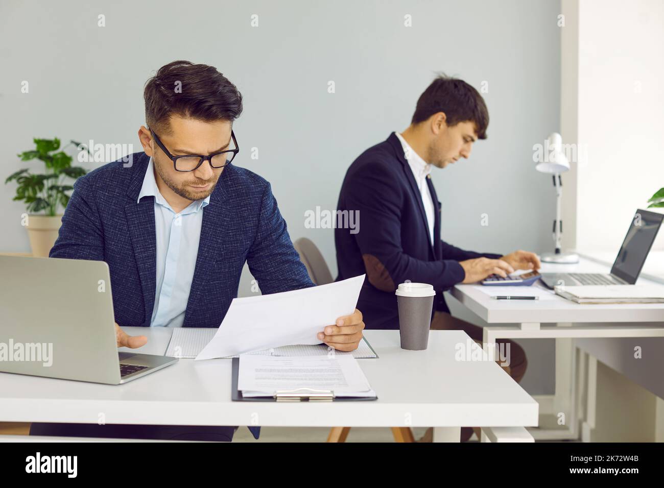 Two serious people sitting at their desks in the office and working ...