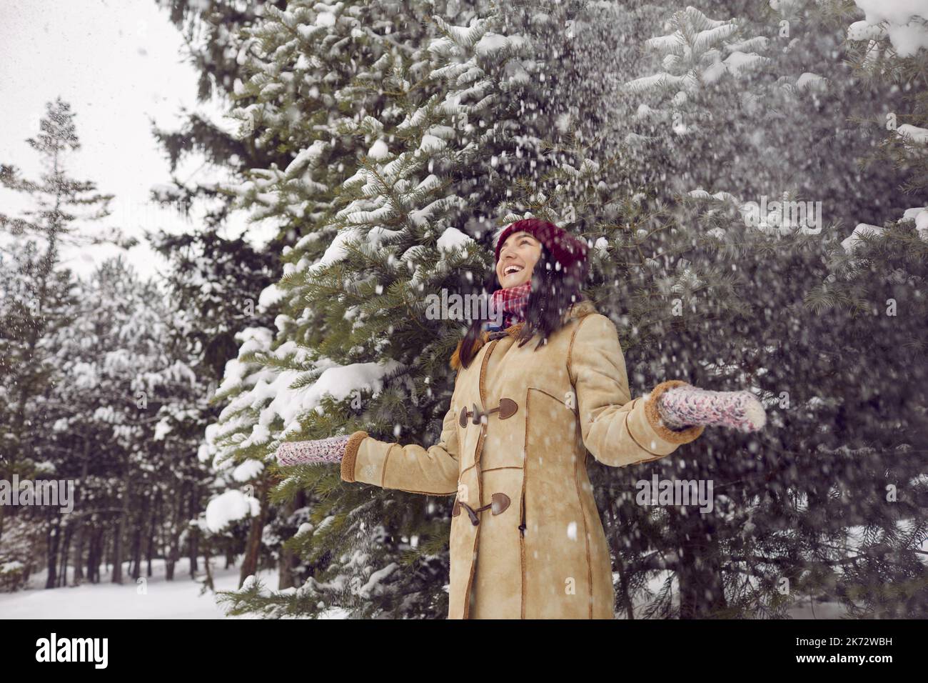 Cheerful young woman having fun and rejoicing in snow falling on her ...