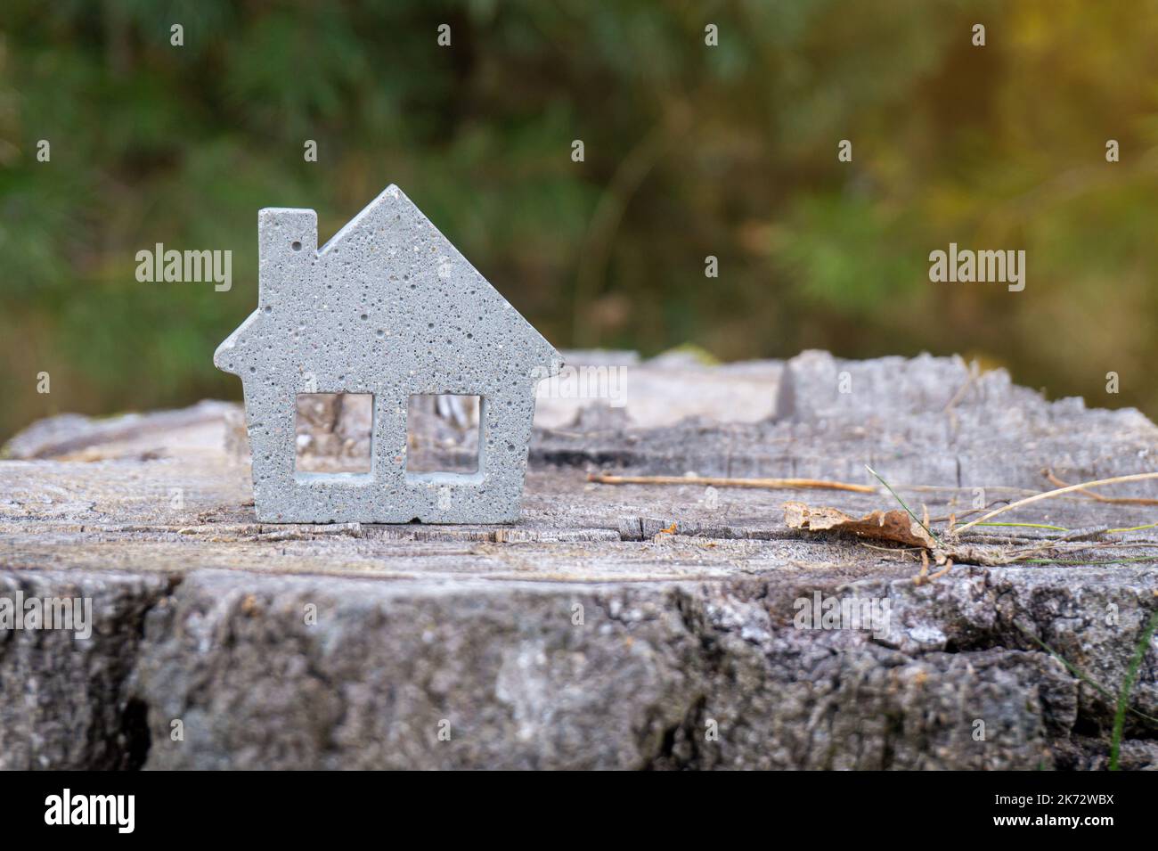 Miniature concrete toy house model on tree stump, copy space. Eco ...
