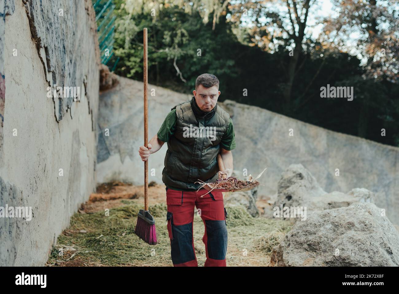 Caretaker with down syndrome in zoo cleaning animal enclosure. Concept ...