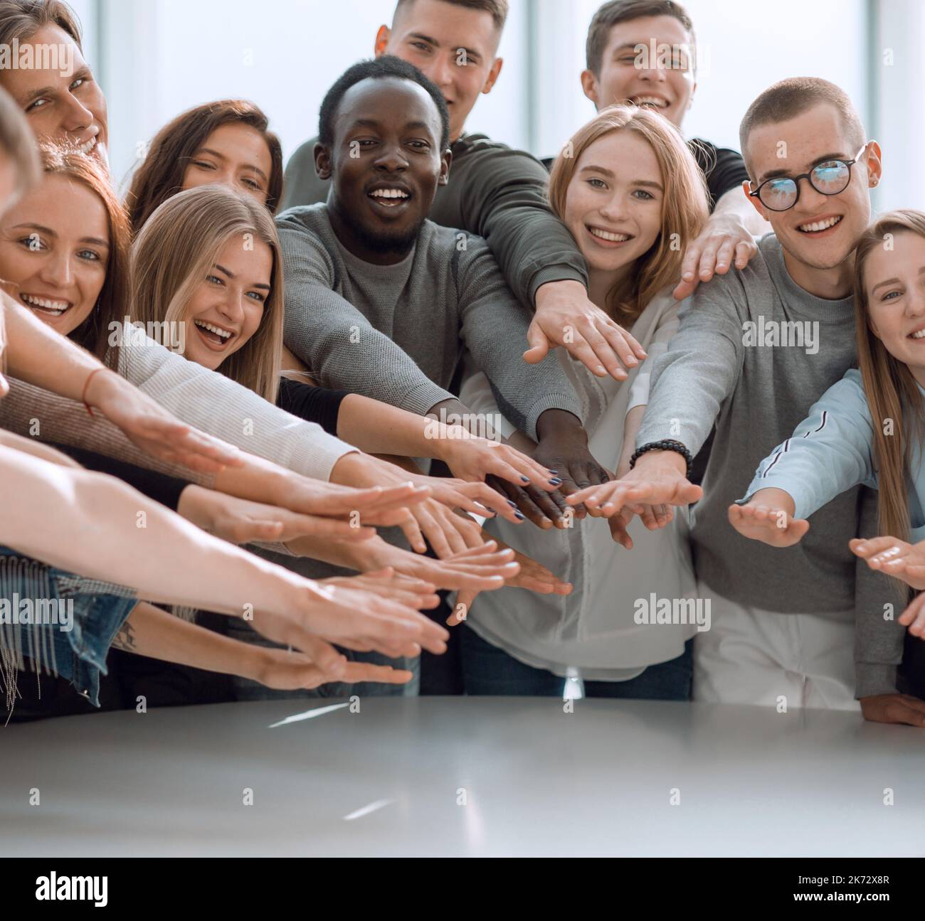 group of smiling young people joining their hands Stock Photo - Alamy