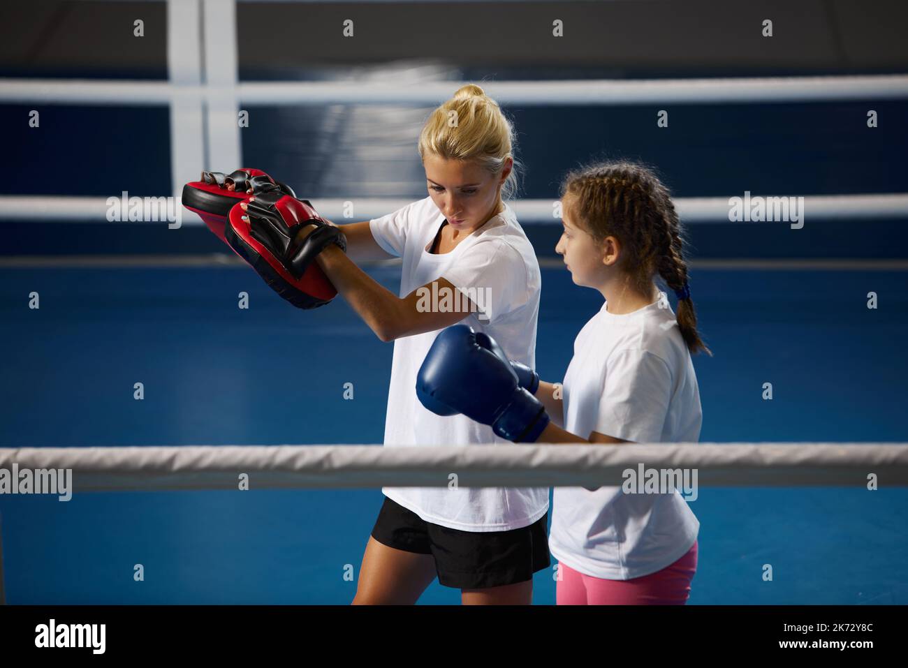 Two athletes, little girl, beginner kickboxer training with female ...