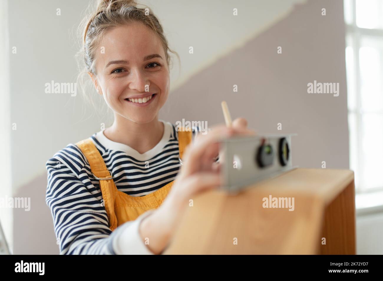 Portrait of young woman remaking shelf in her new flat. Concept of ...