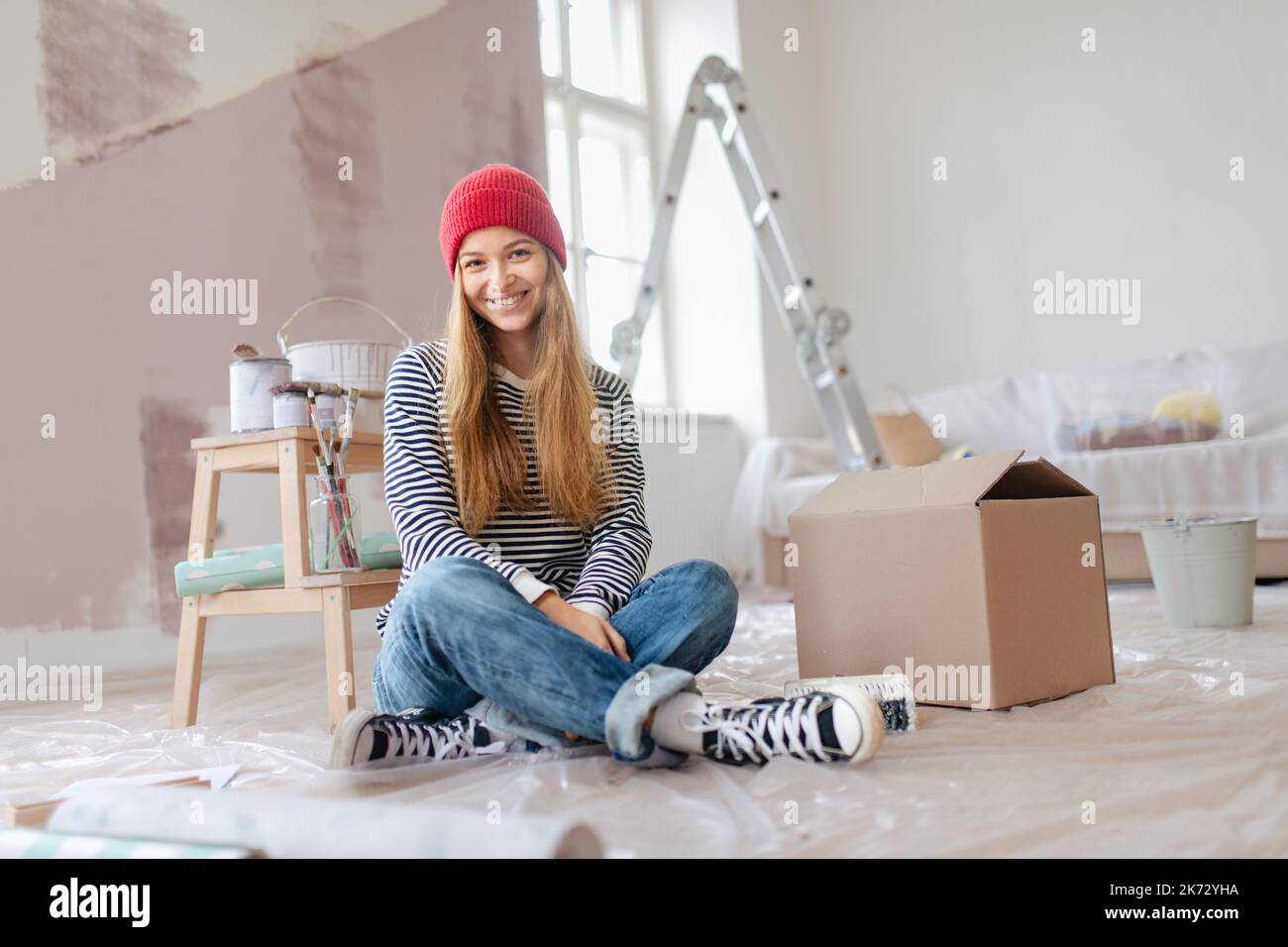 Happy young woman having break during painting walls in her aparatment ...