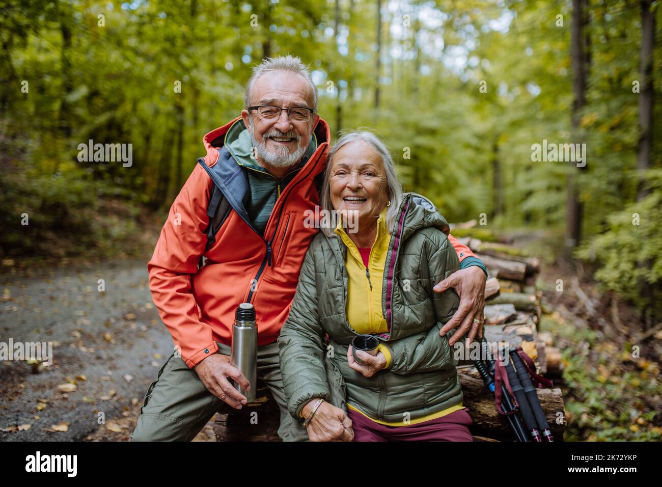 Senior couple having break during hiking in autumn forest Stock Photo ...