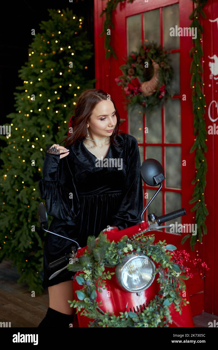 Beauty portrait of a woman on a red scooter moped, Christmas interior ...