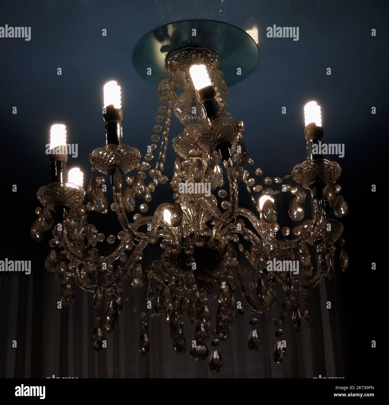 Modern electric bulbs shines in ceiling chandelier in old classic style ...