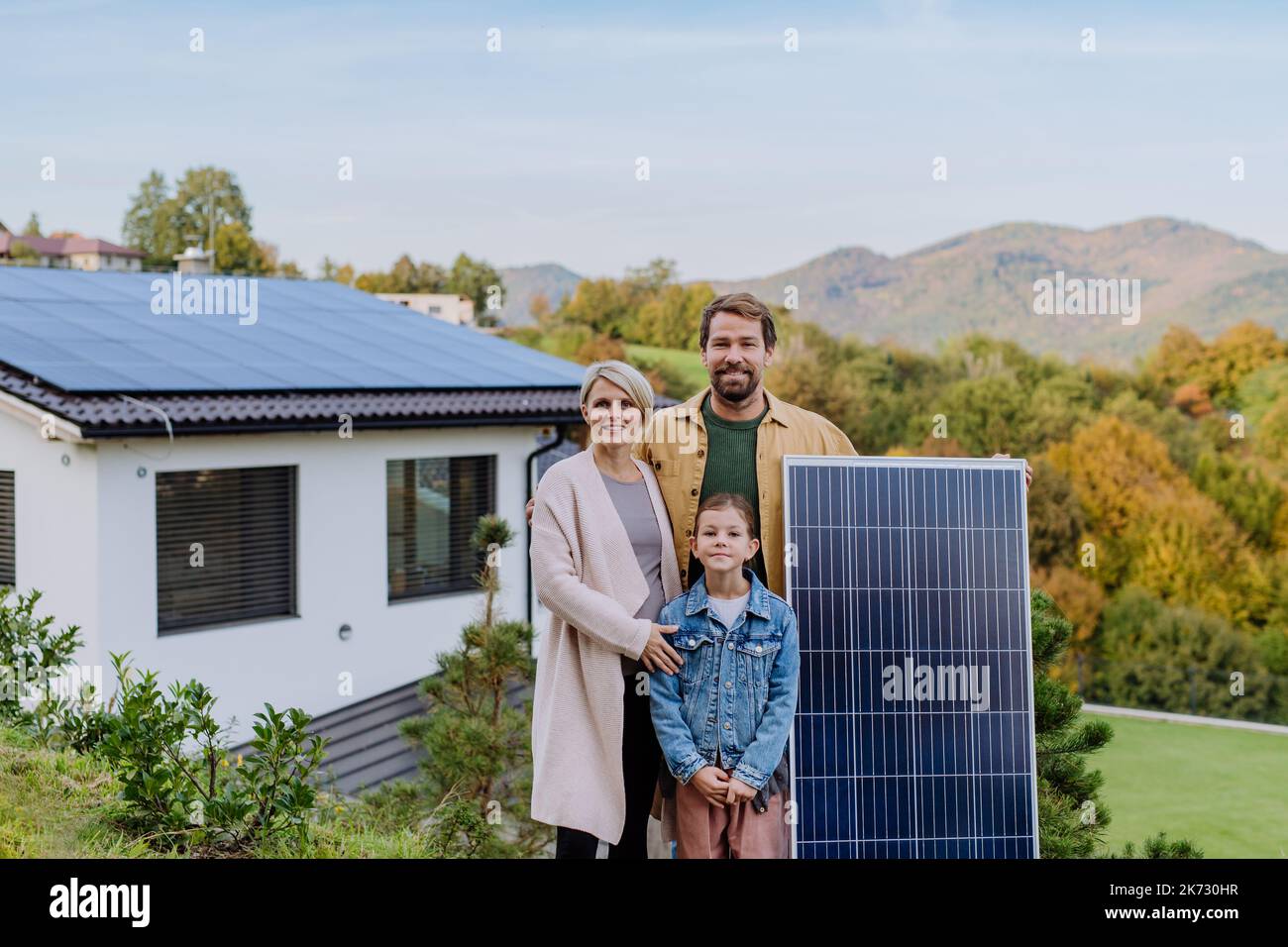 Happy family near their house with solar panel. Alternative energy ...