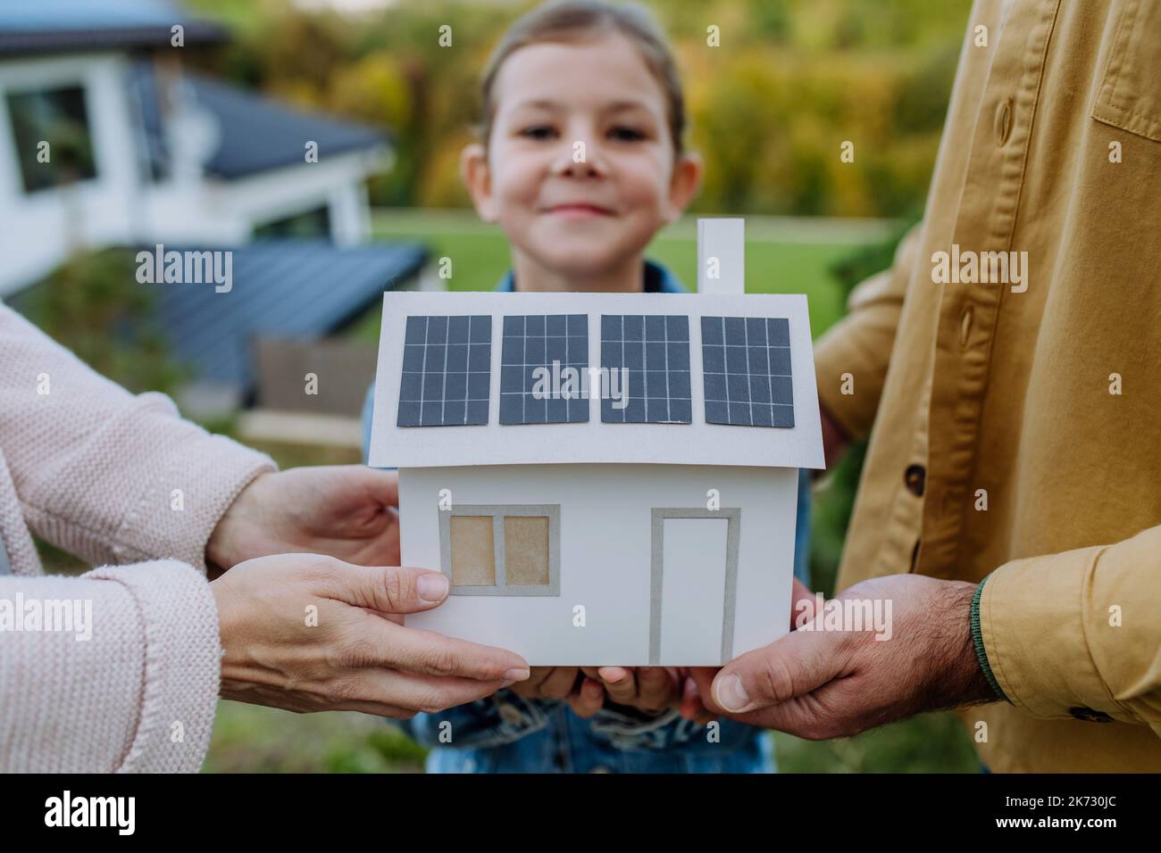 Close up of young family holding paper model of house with solar panels ...