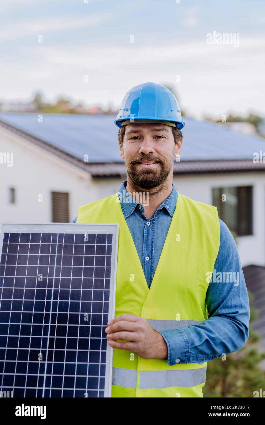 Smiling handyman solar installer standying with solar module while ...