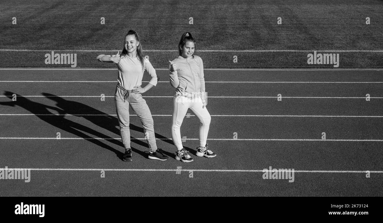 Happy fit girls show thumbs up standing on athletics track, physical ...