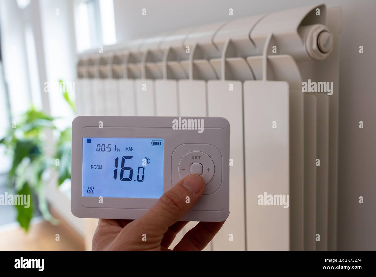 Close up of thermostat heating control panel with heater in background ...