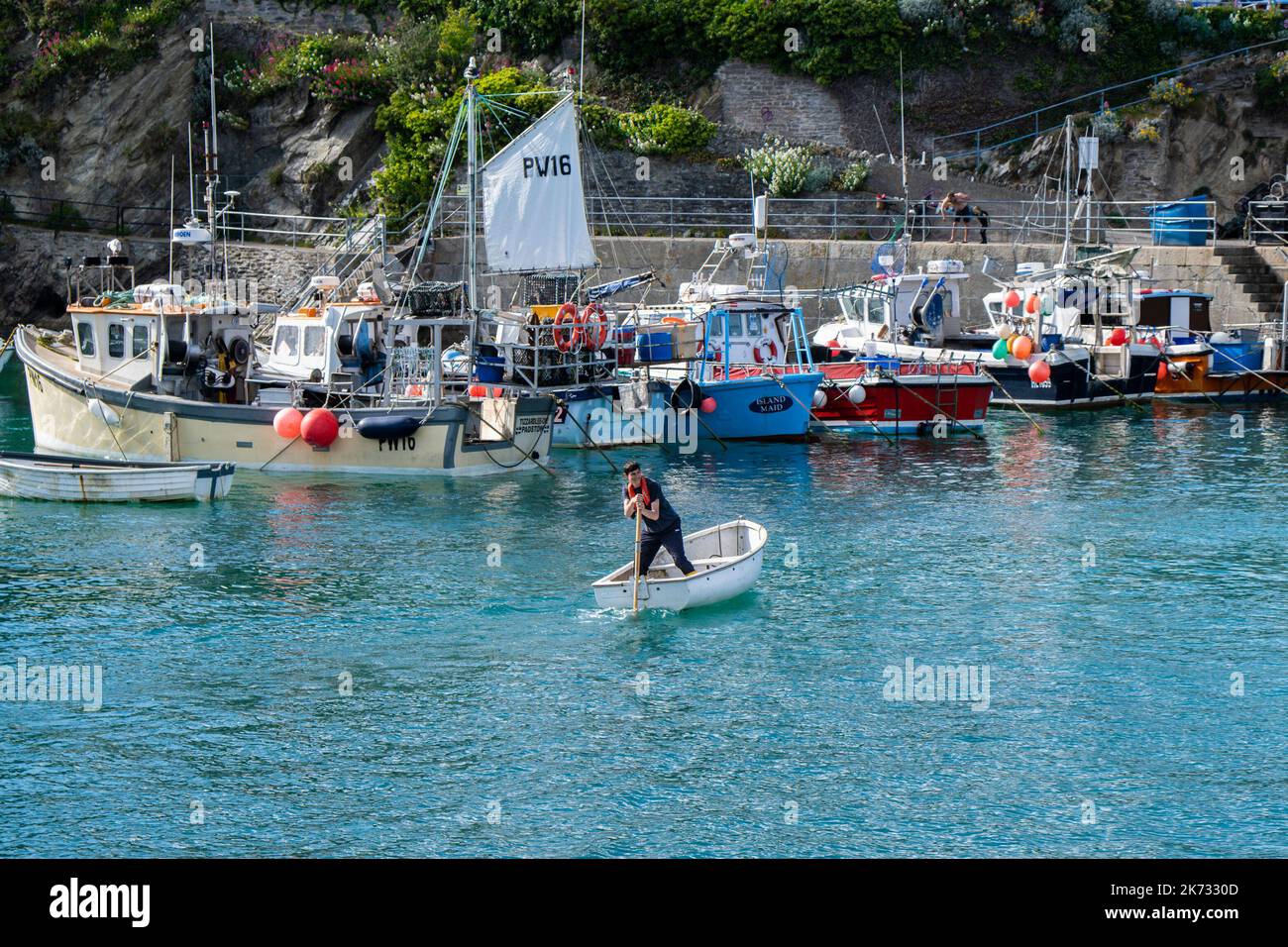 A man sculling over the stern of a dinghy in the picturesque quaint ...
