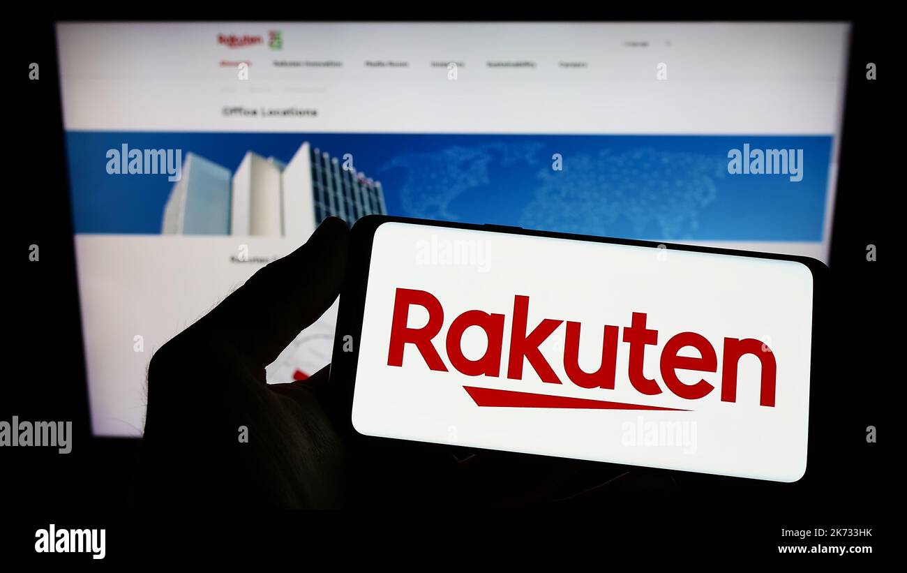 Person holding mobile phone with logo of Japanese e-commerce company Rakuten Group Inc. on ...